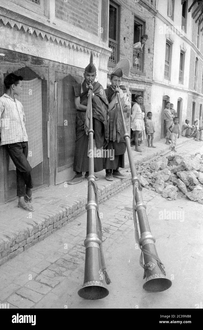 Two monks blow long horn instruments in a street in Kathmandu Stock ...