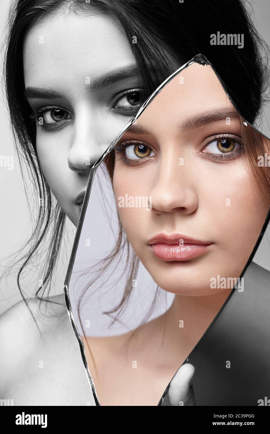 Monochrome portrait of female with mirror shard in hand posing on gray ...