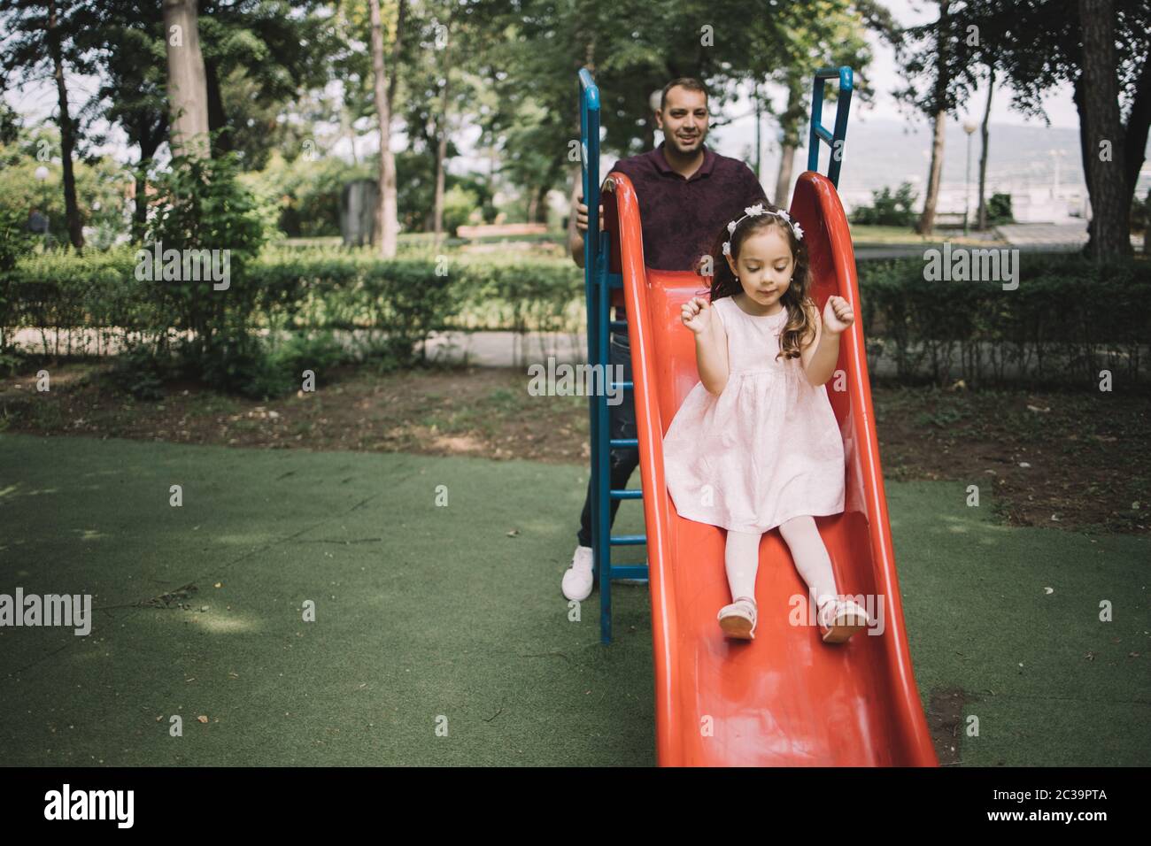 Girl sliding on slide with her father Stock Photo - Alamy