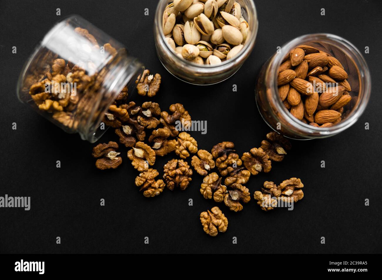 Walnut scattered on the black table from a jar. Walnut is a healthy ...