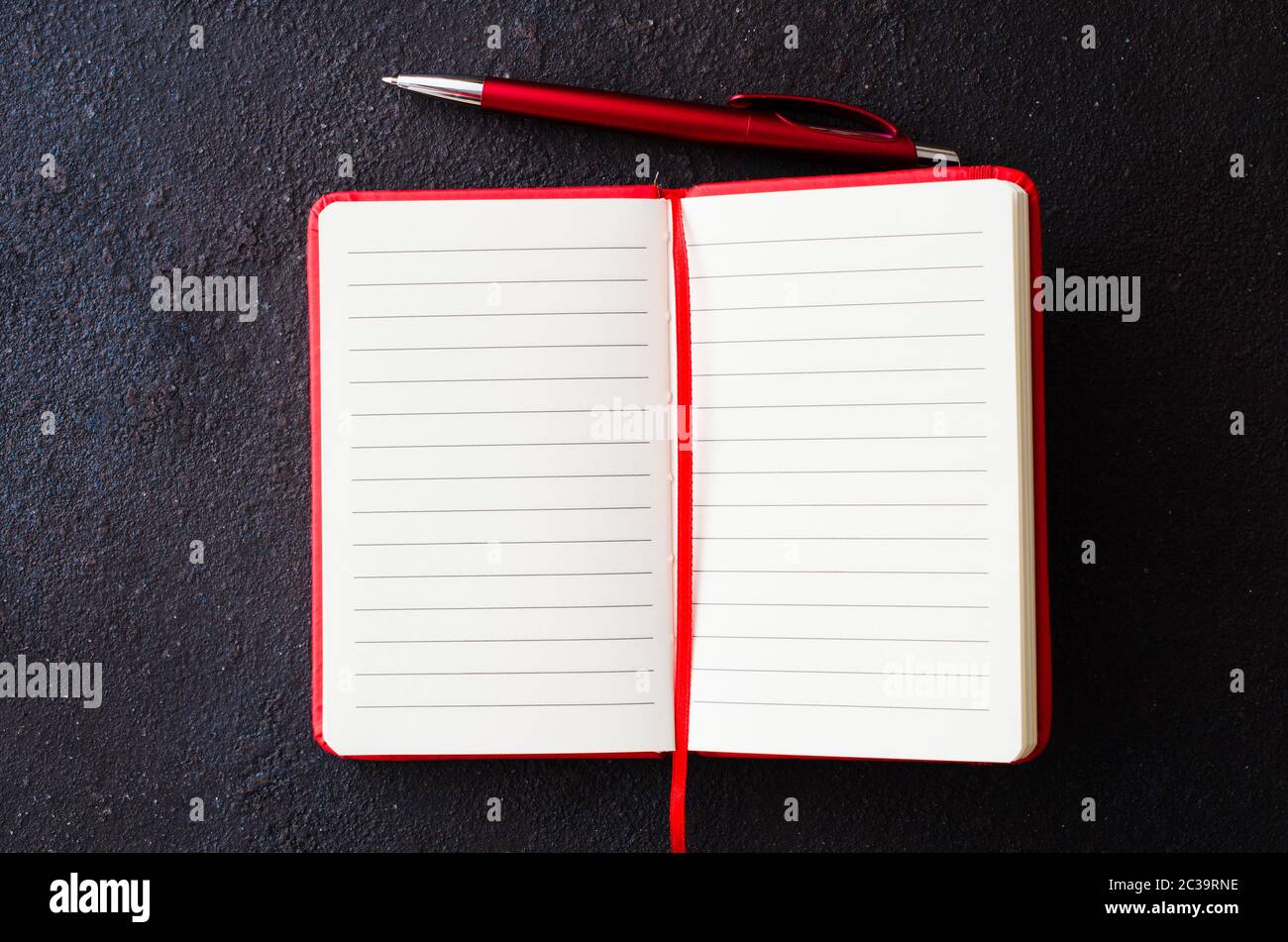 Empty red notebook with red pen on dark background. Blank paper for ...