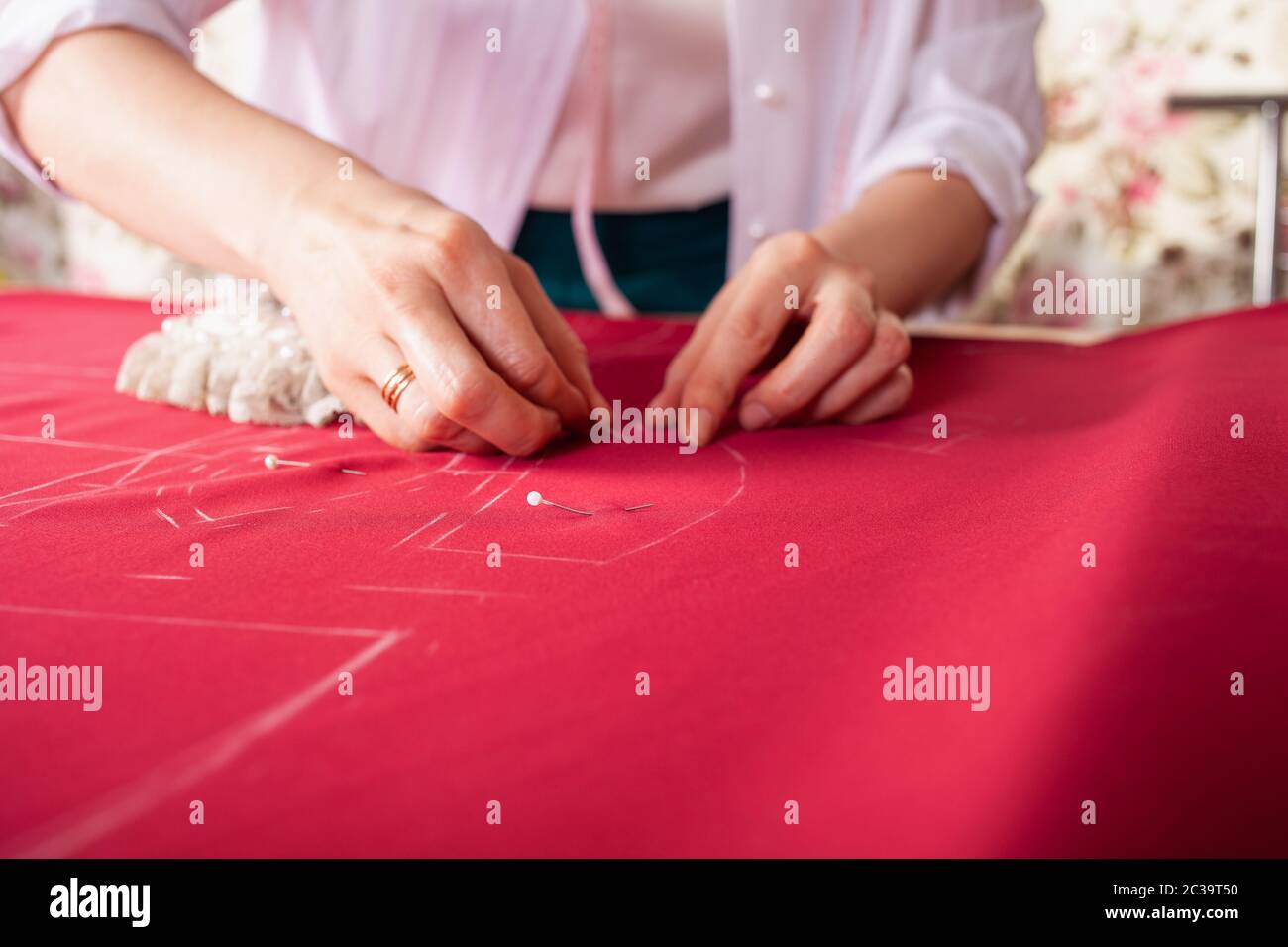 The master seamstress rocks two parts of the fabric with pins. A woman ...