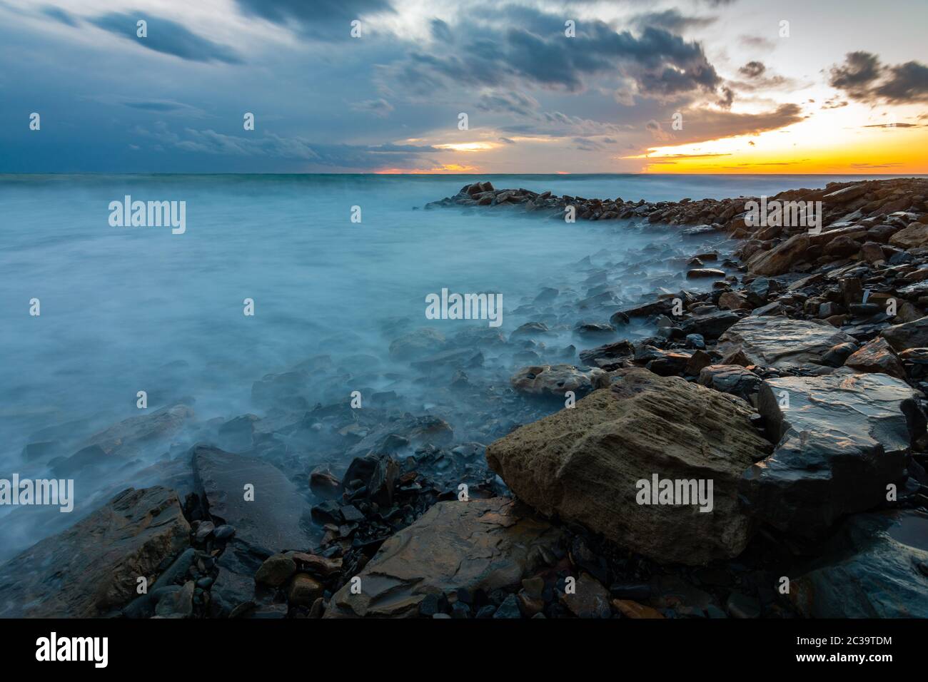Seascape at sunset, waves roll ashore Stock Photo - Alamy