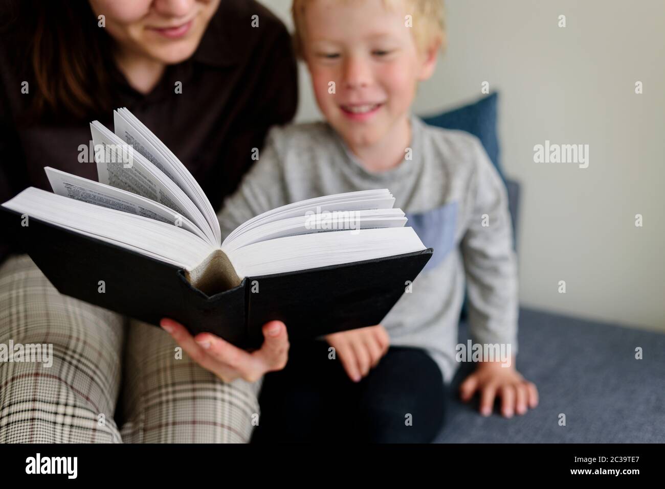 Mother and child reading book and smiling. Happy family time together ...