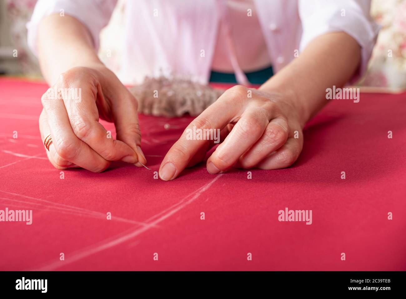 The master seamstress rocks two parts of the fabric with pins. A woman ...