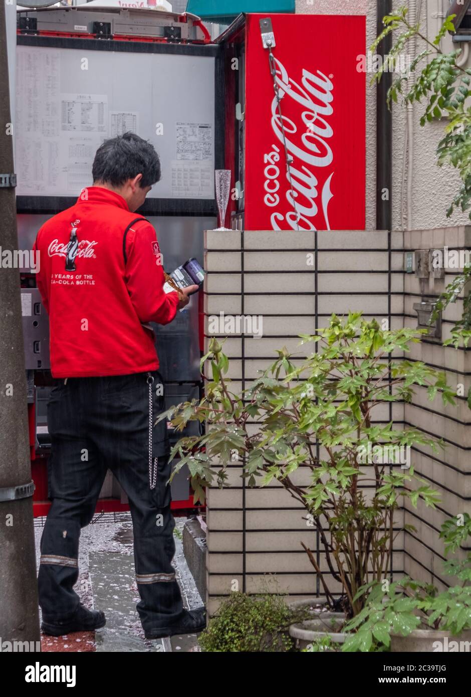Man delivering and stocking up Coca Cola drinks at Nakameguro ...