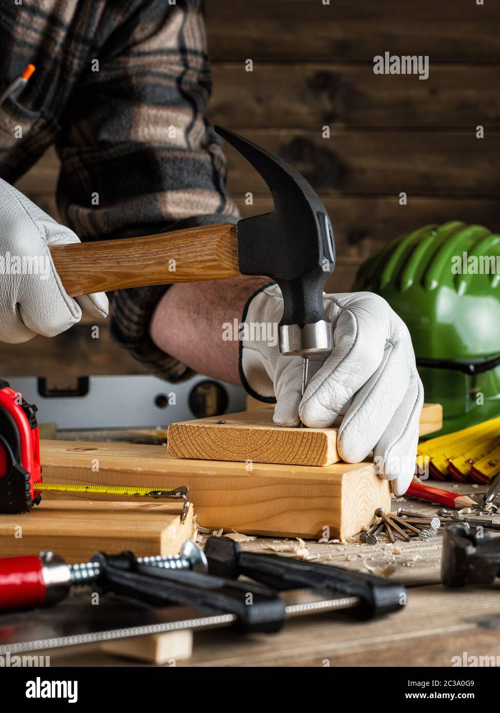 Close-up. Carpenter with his hands protected by gloves, with hammer and ...