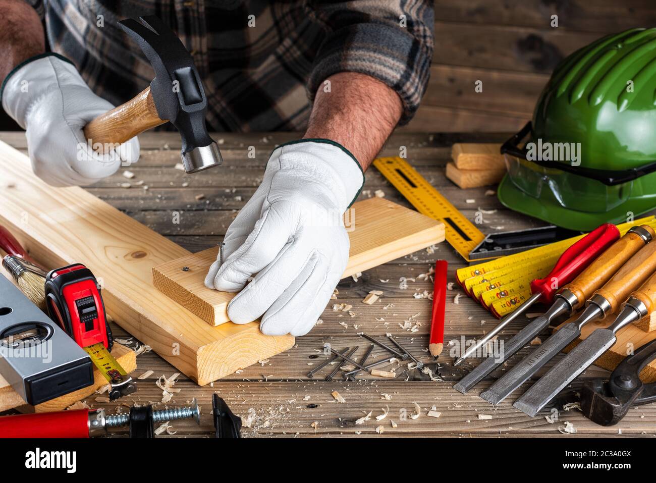 Close-up. Carpenter with his hands protected by gloves, with hammer and ...