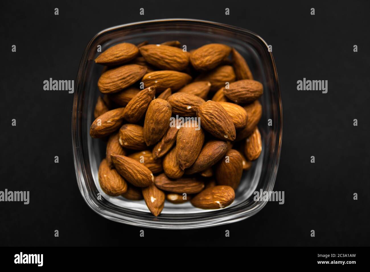 Almonds in a small plate on a black table. Almond is a healthy ...