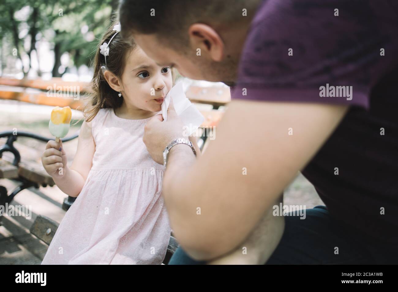 Father cleaning his daughter's face after eating ice cream Stock Photo ...