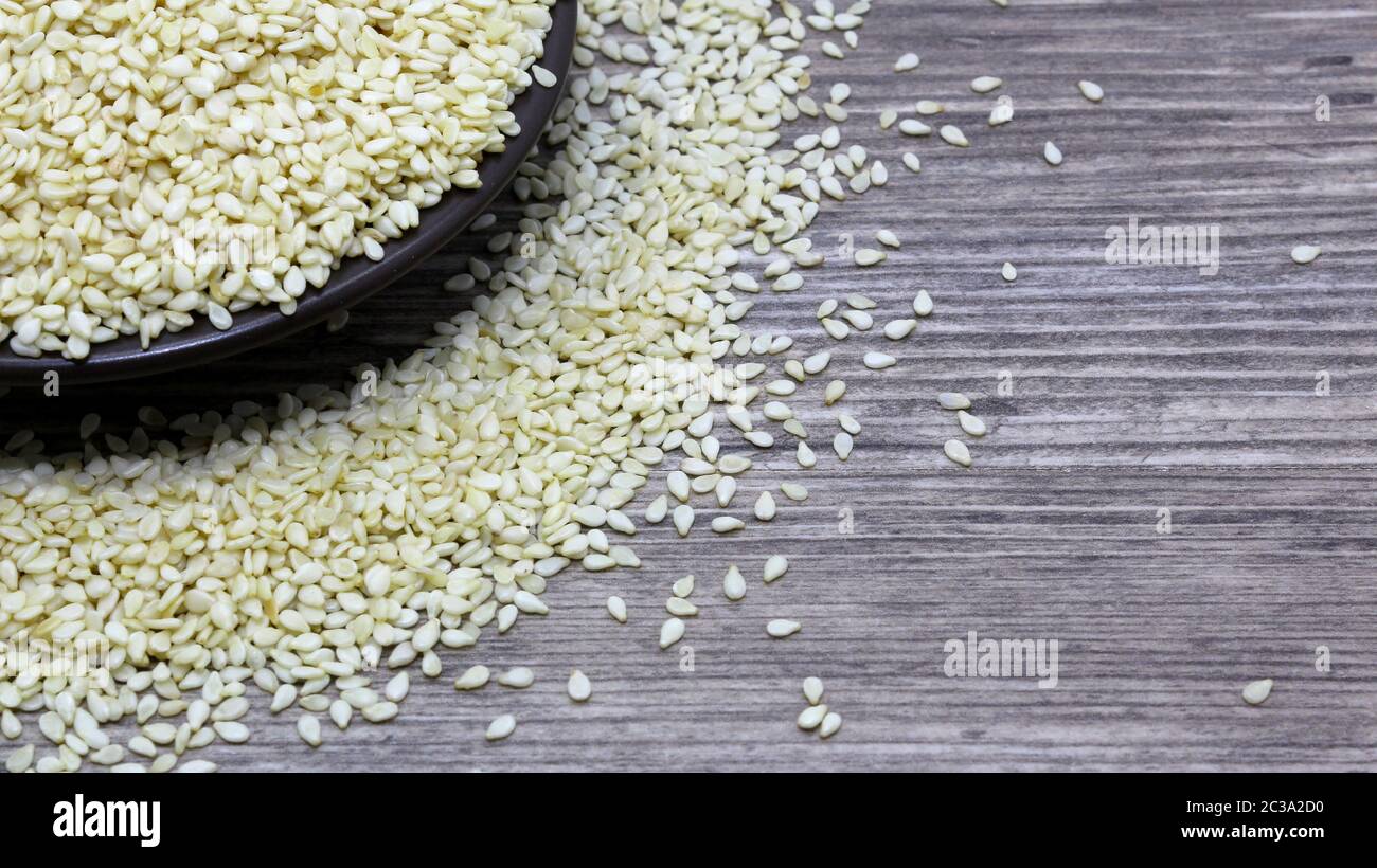 sesame seeds scattered on the plate on wooden background Stock Photo ...