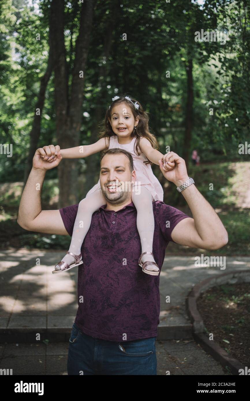 Man standing in park and holding child on shoulders Stock Photo - Alamy
