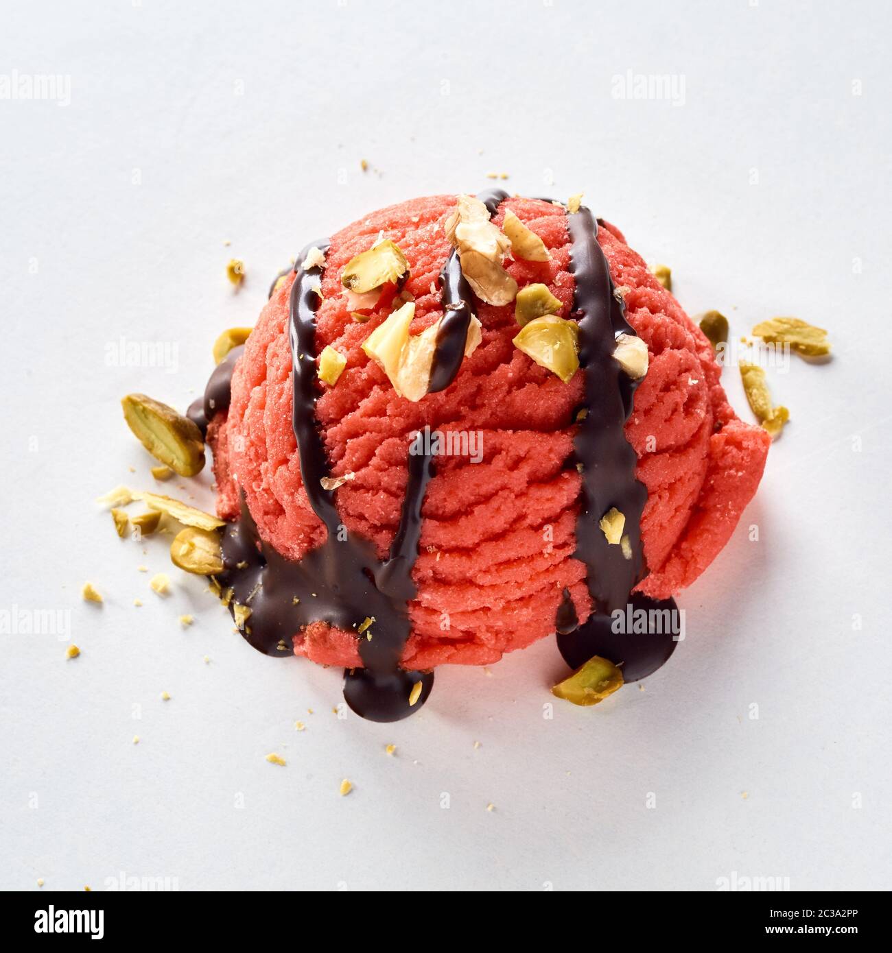 Red berry ice-cream topped with pistachio nuts and drizzled chocolate ...