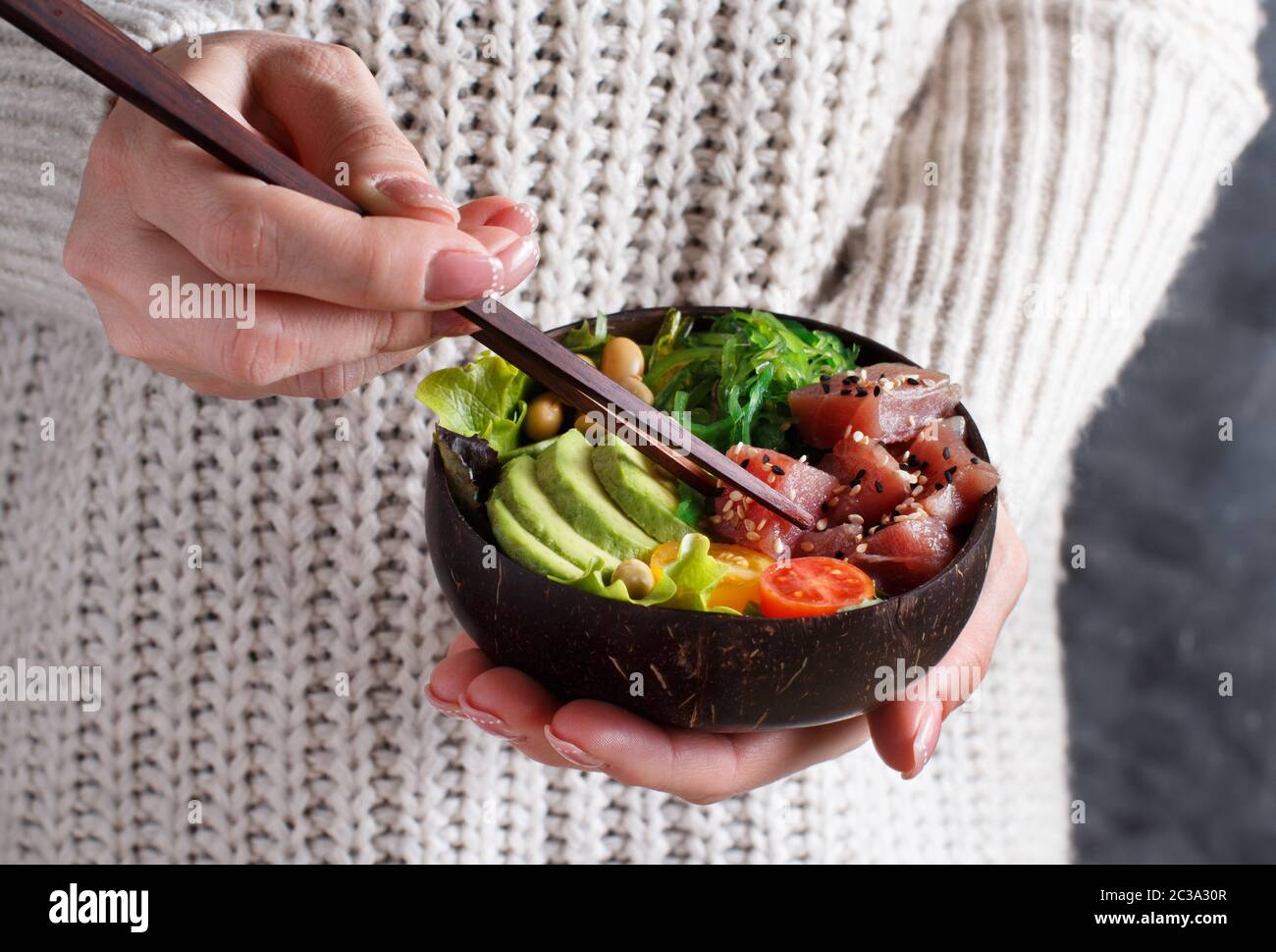 Girl eating hawaiian tuna poke salad in the bowl Stock Photo - Alamy