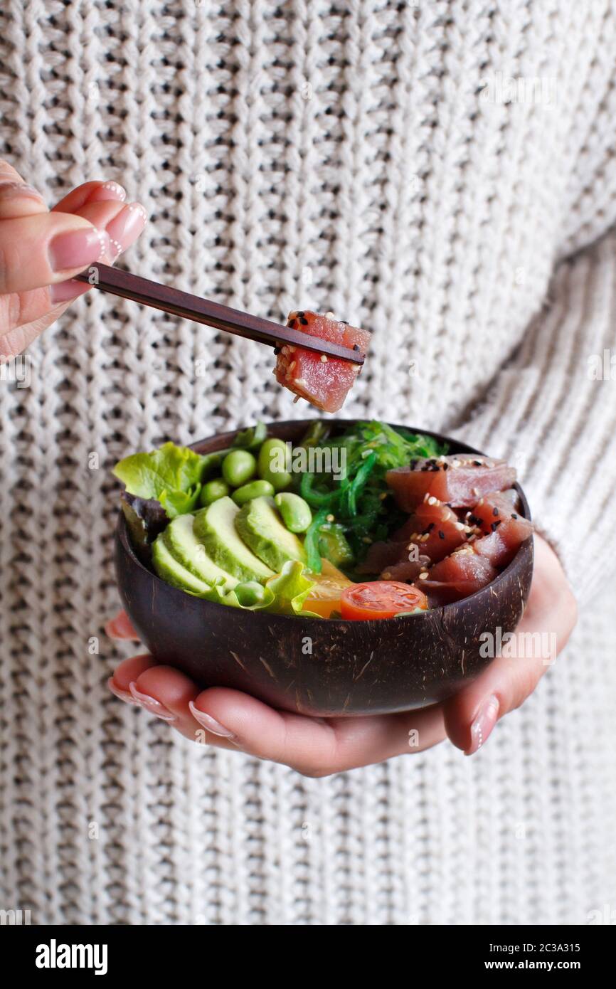 Girl eating hawaiian tuna poke salad in the bowl Stock Photo - Alamy
