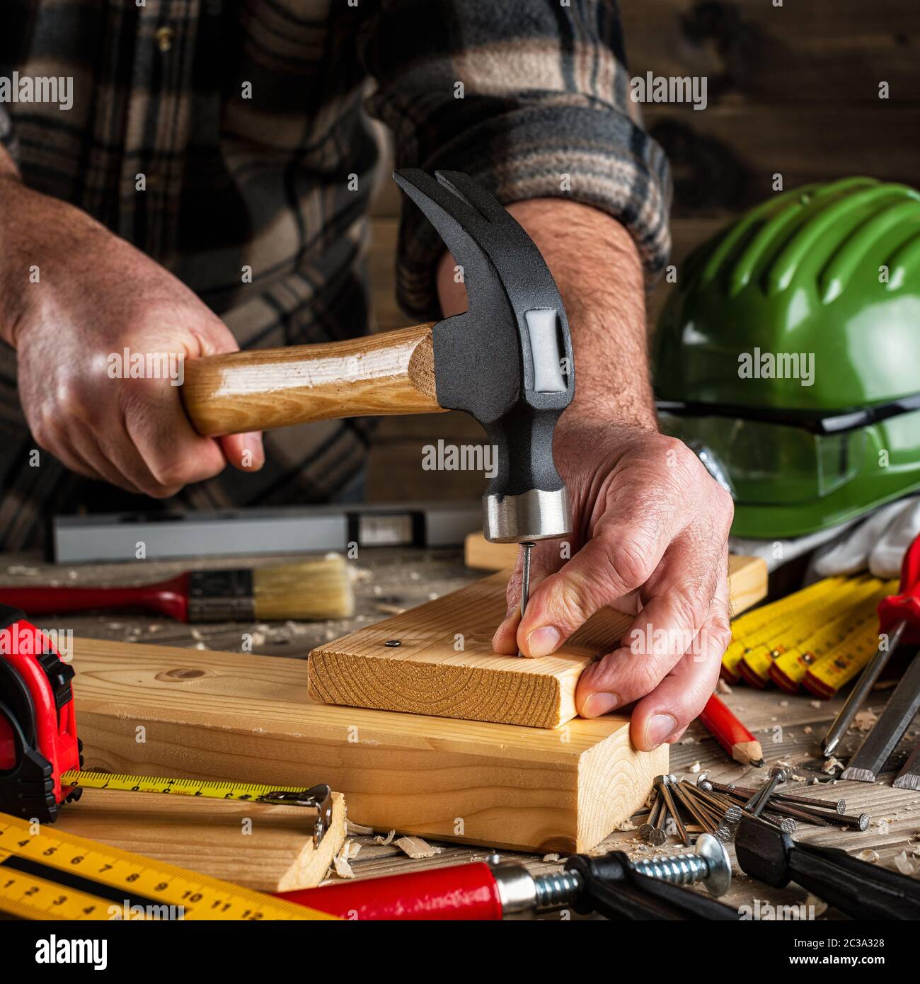 Close-up. Carpenter with hammer and nails fixes a wooden board ...