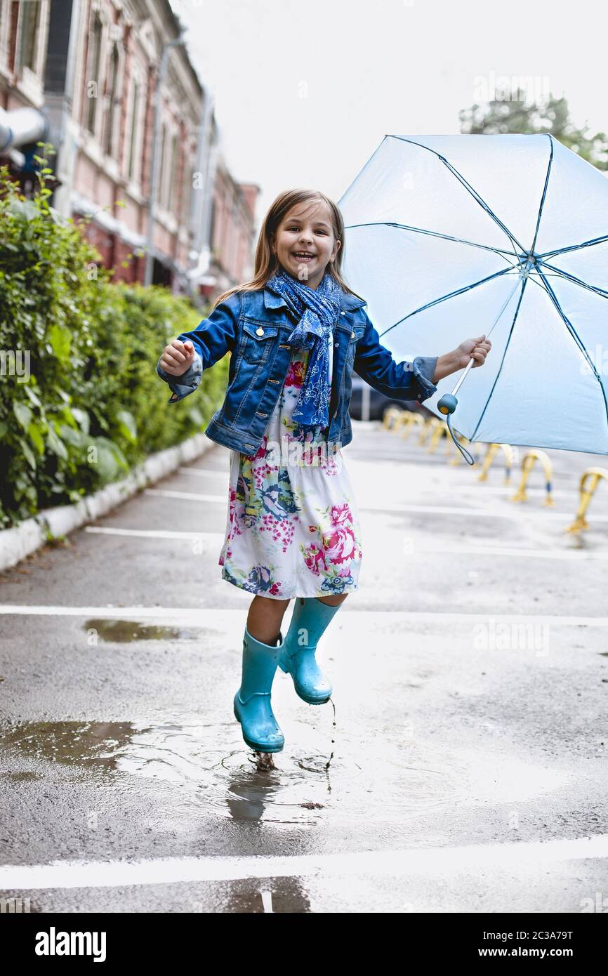 Cheerful small girl having fun in puddle on street Stock Photo - Alamy