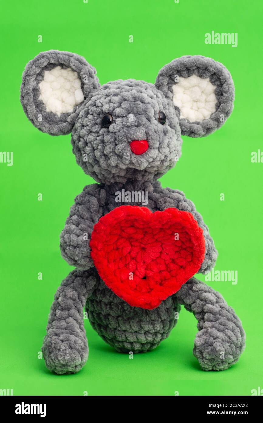 Grey knitted mouse with a heart in hand on a green background Stock ...
