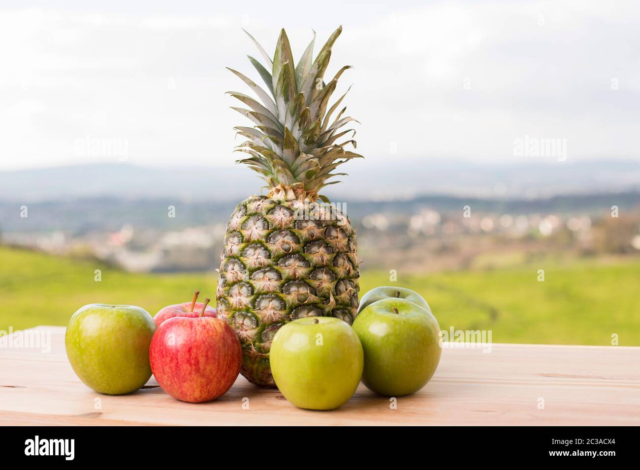 Pineapple and apple on wood table, outdoor Stock Photo - Alamy