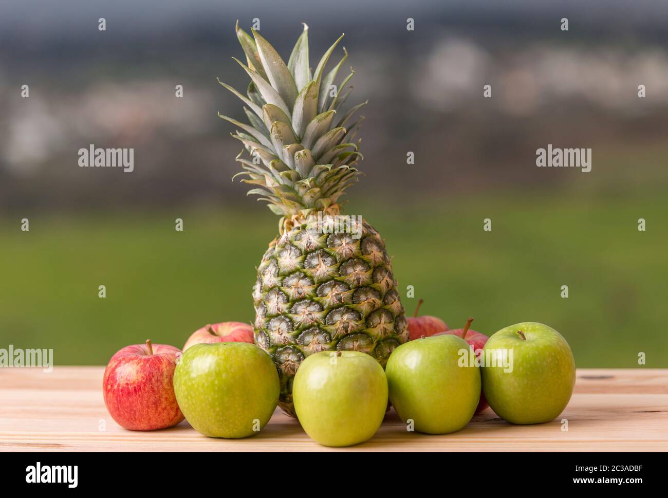 Pineapple and apple on wood table, outdoor Stock Photo - Alamy