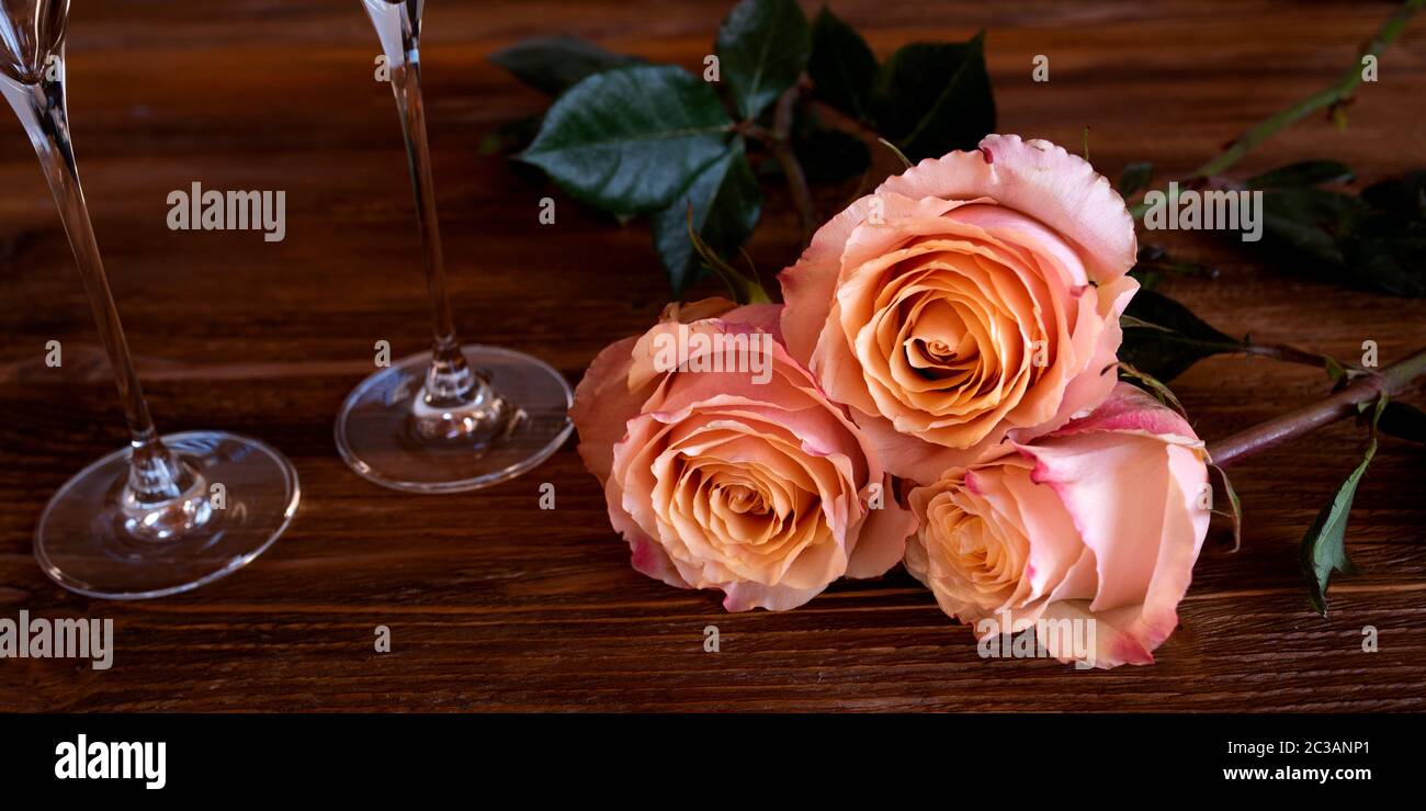 Tender pink roses with two champagne glasses on dark vintage wooden ...