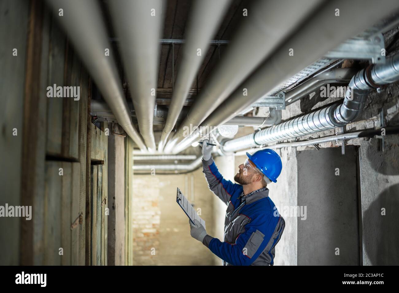 Male Worker Inspecting Water Pipes For Leaks In Basement Stock Photo ...