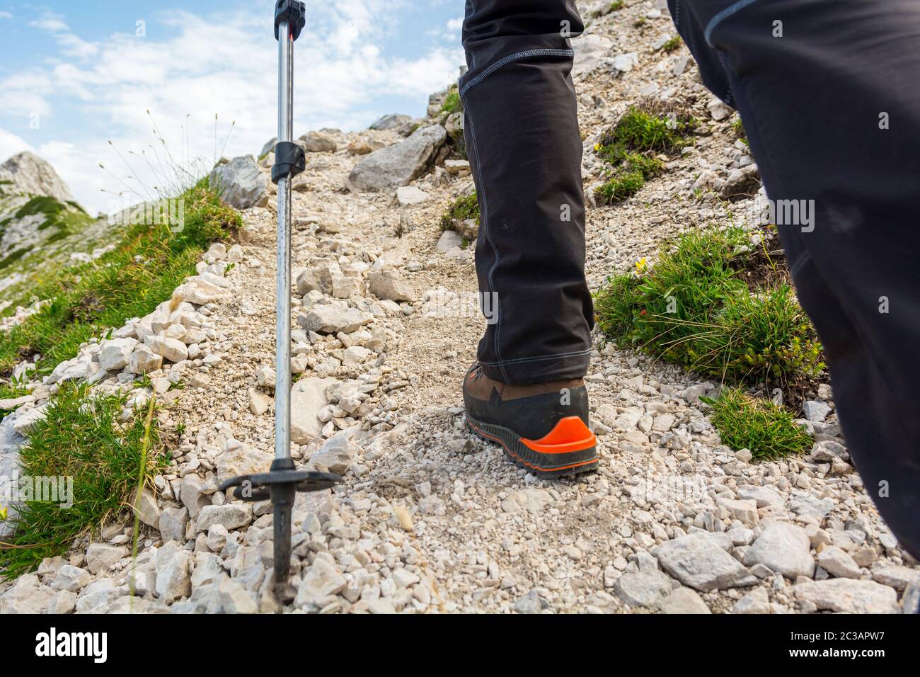 Hiker ascending a mountain and walking path upwards using poles Stock ...