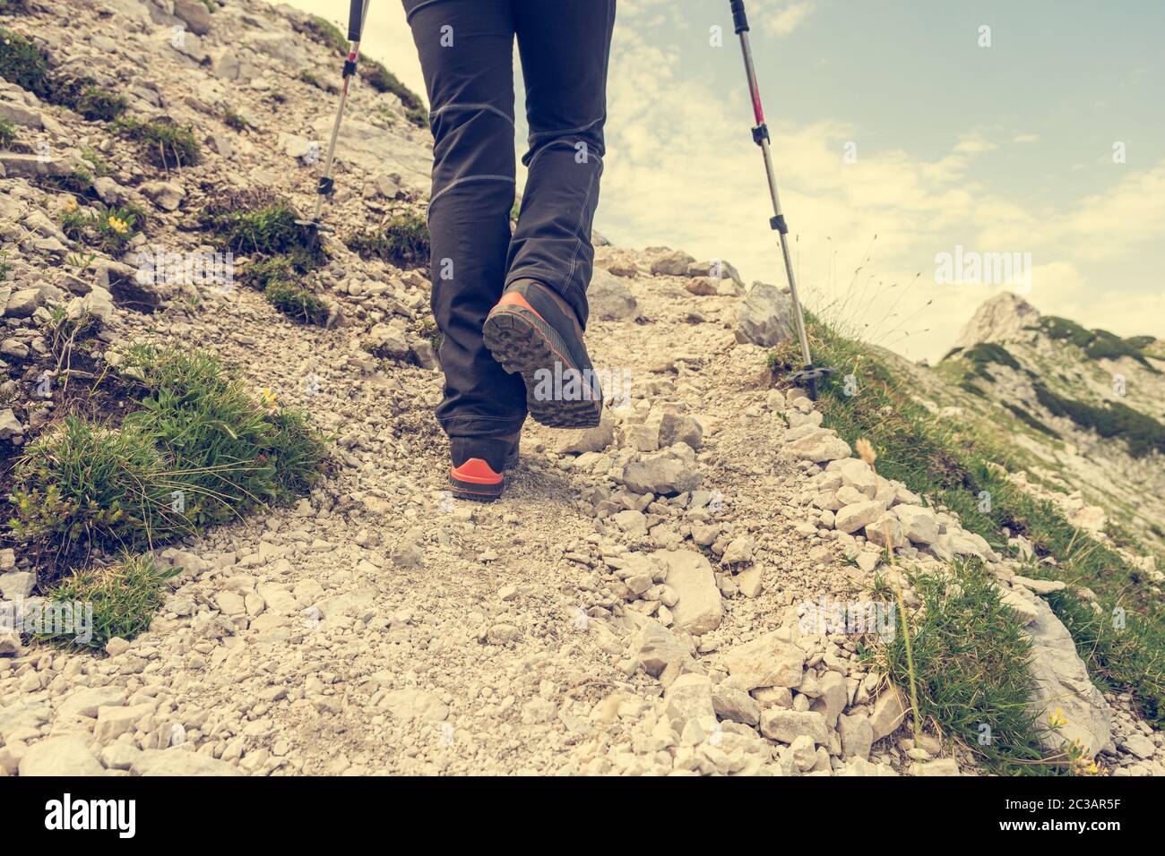 Hiker ascending a mountain and walking path upwards using poles Stock ...