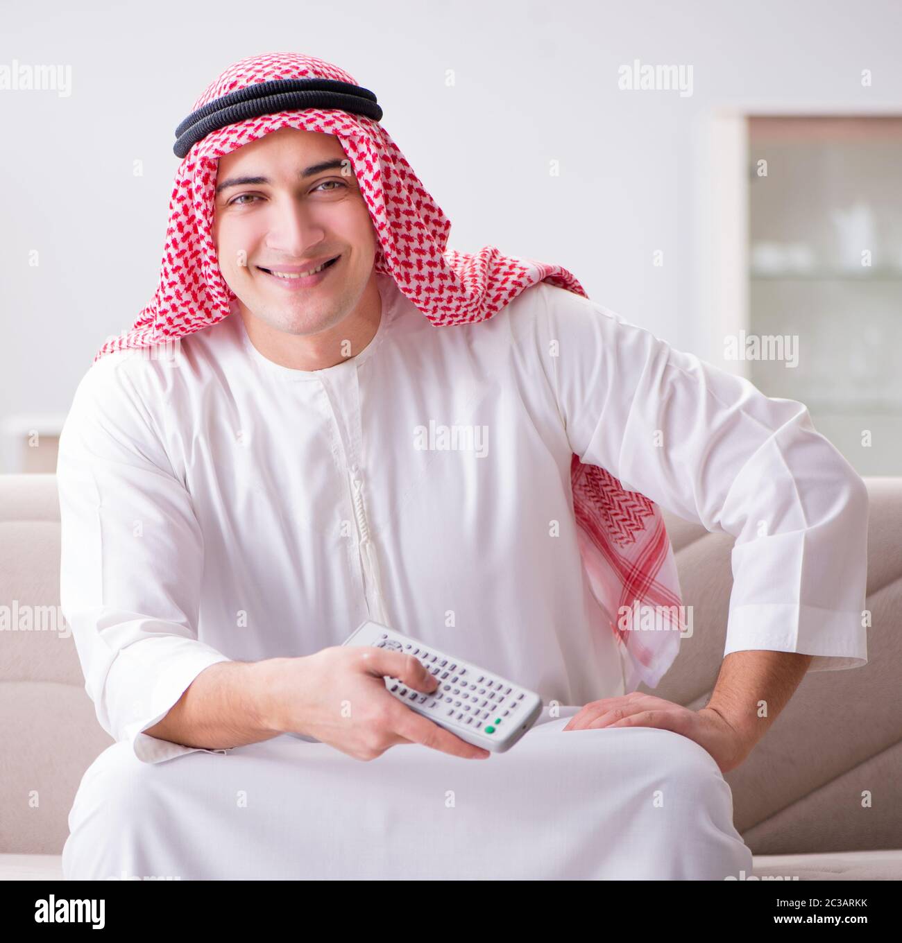 Young arab man watching tv sitting on the sofa Stock Photo - Alamy