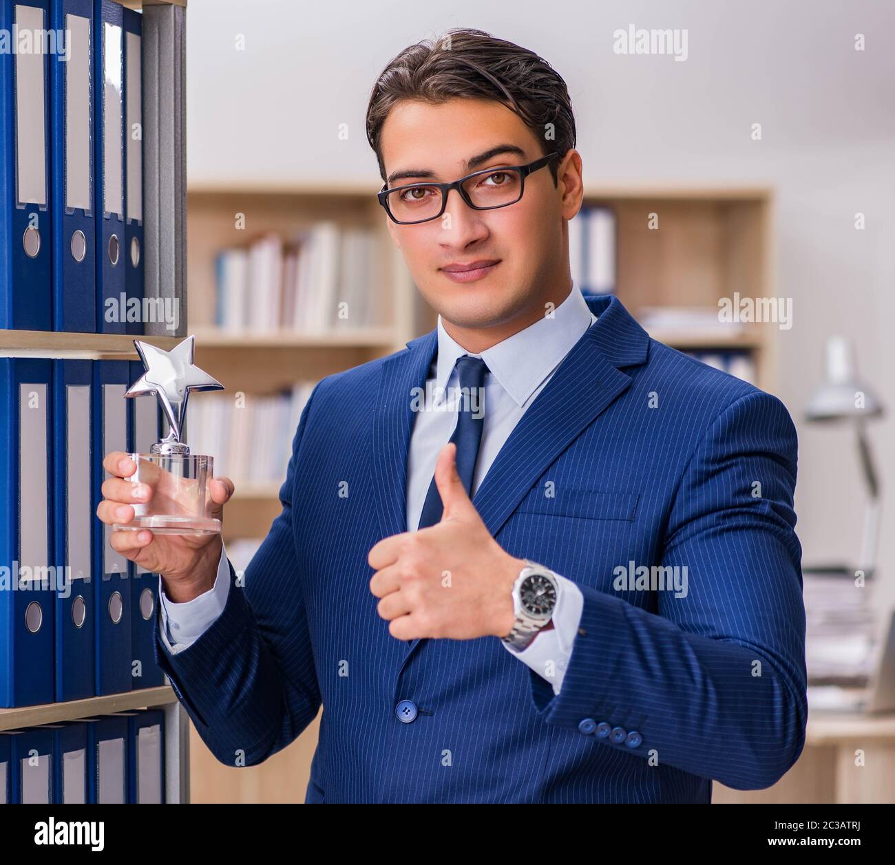 Young man standing next to the shelf with folders Stock Photo - Alamy