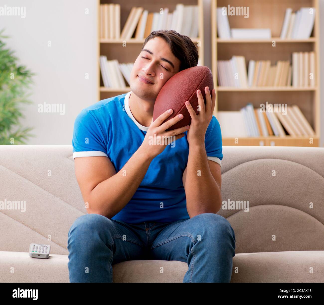 Man watching football at home sitting in couch Stock Photo - Alamy