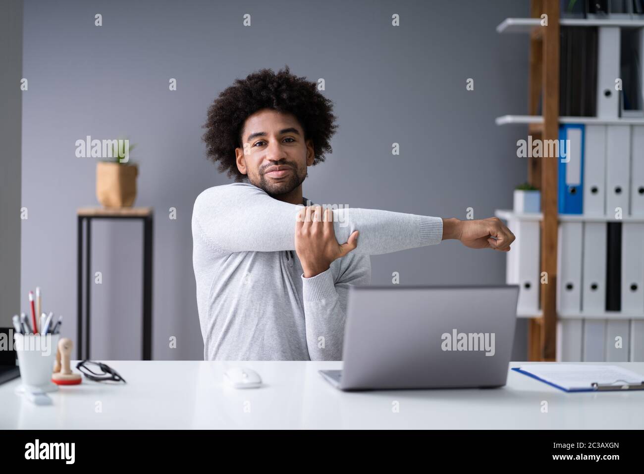 Young Businessman Stretching His Arms With Laptop On Desk Stock Photo ...
