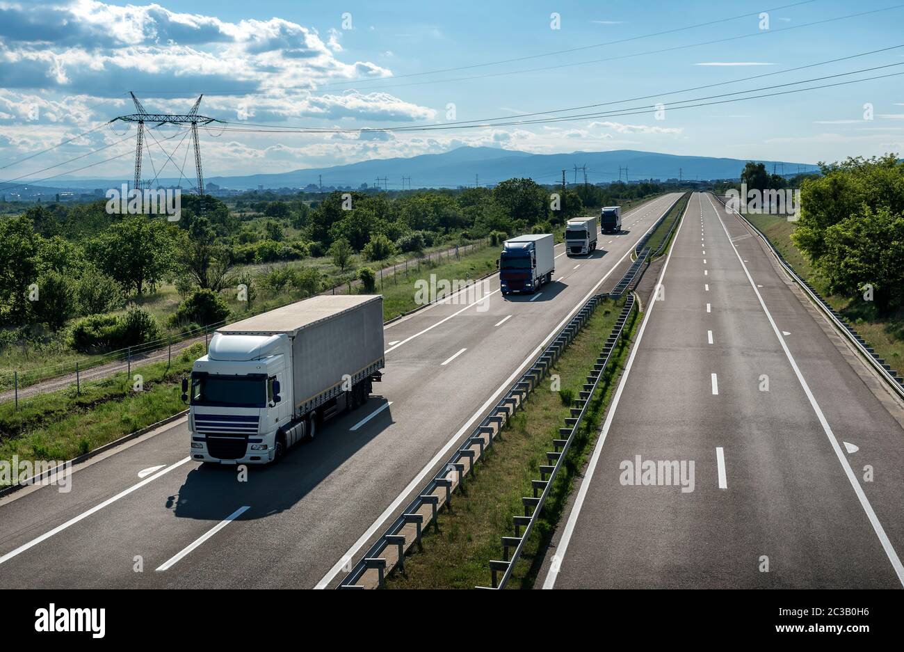 Highway transportation with a convoy of four Lorry trucks passing ...