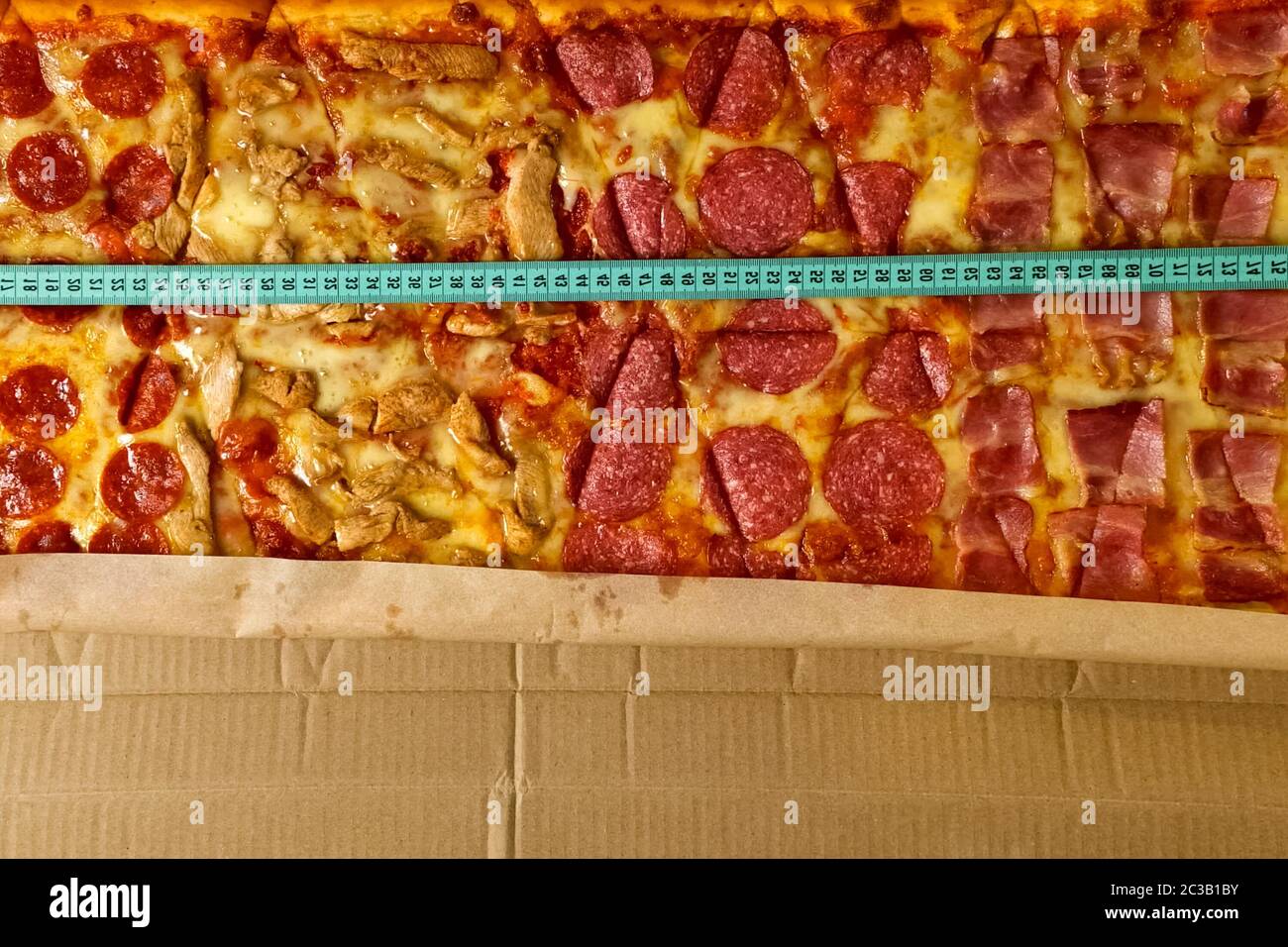 Long big sausage pizza. Measure pizza length with a tape measure Stock ...