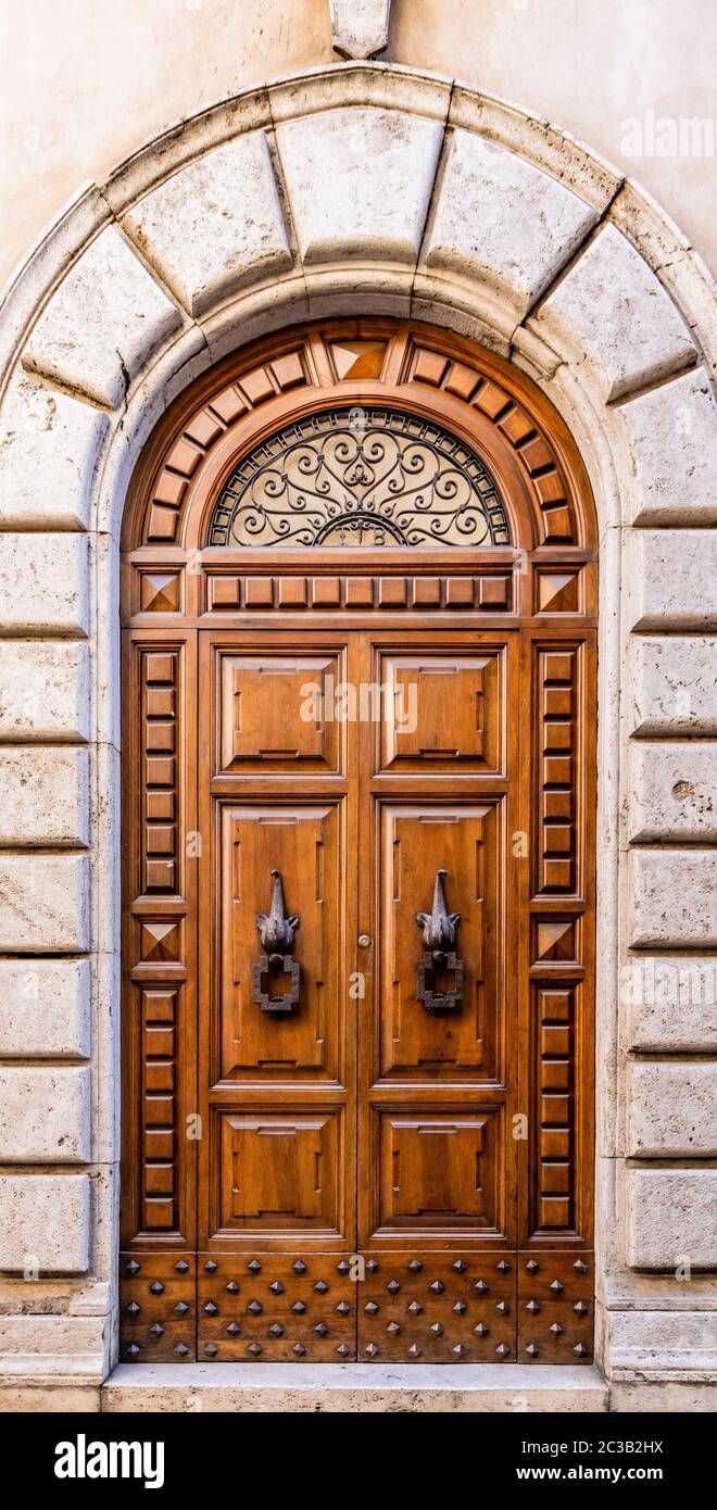 An ancient wooden portal with iron knocker, arch and window with metal ...
