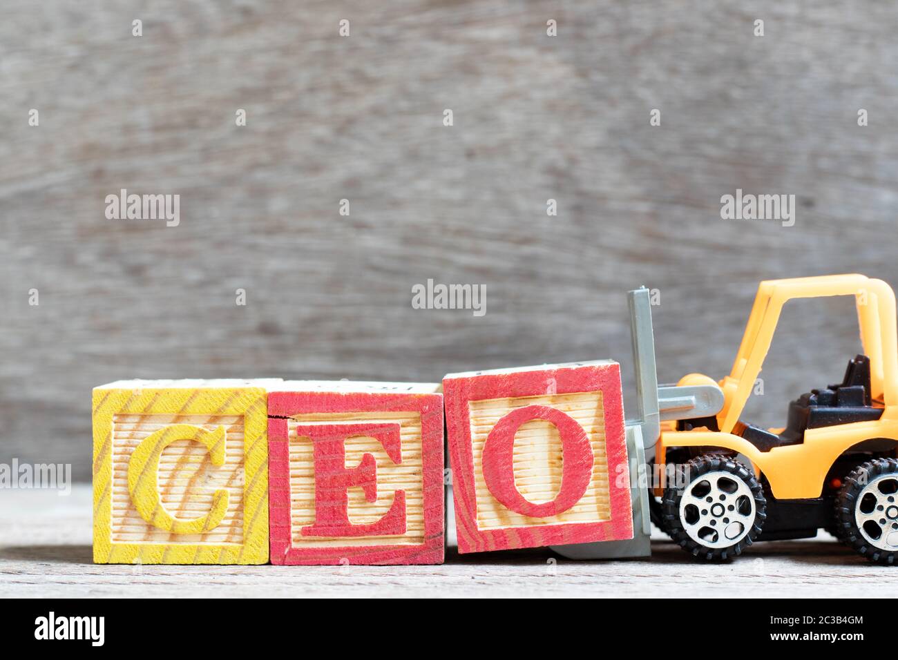 Toy forklift hold letter block O to complete word CEO (abbreviation of ...