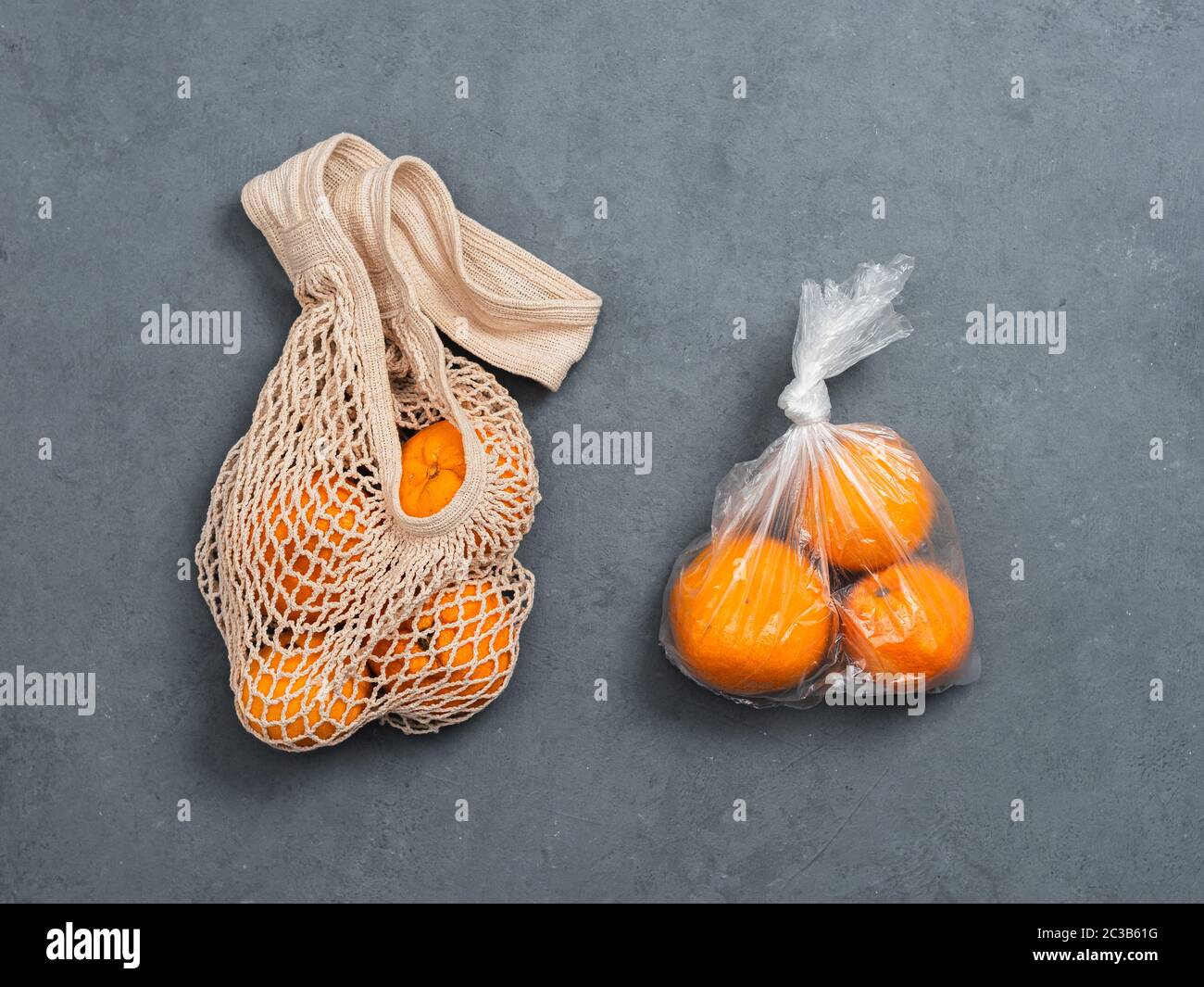 Oranges fruits in plastic bag and oranges in textile mesh bag on gray ...