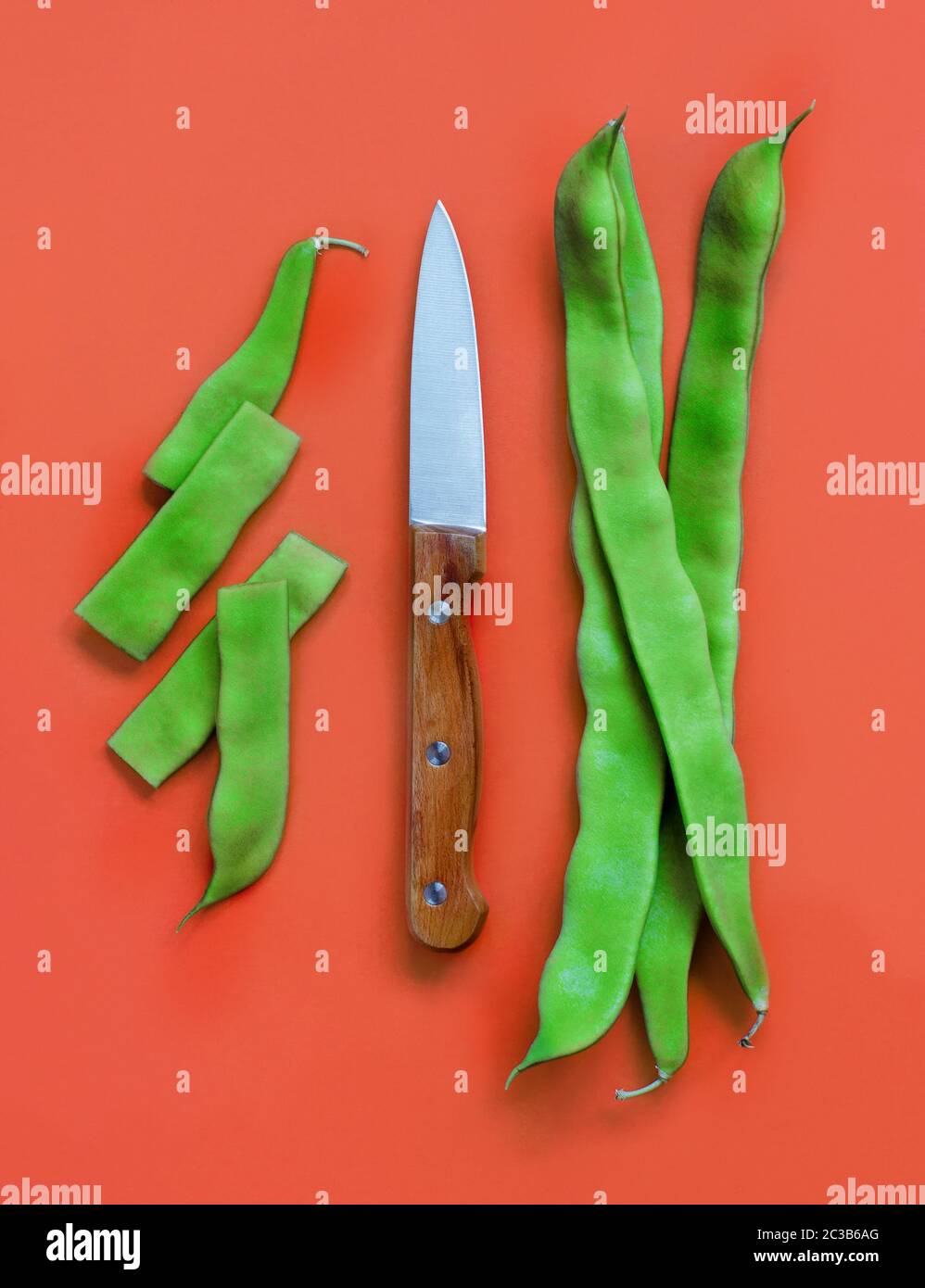 Piattoni green beans top view with a knife on a coral red background ...