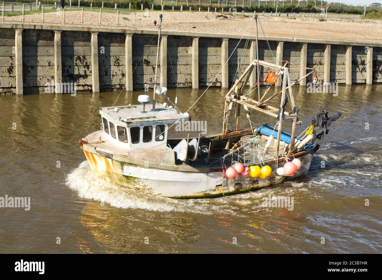 Fishing boat motoring out to sea on the River Arun at Littlehampton ...