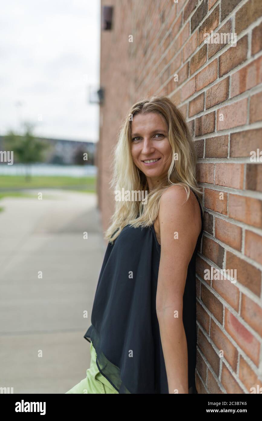 Woman standing against brick wall hi-res stock photography and images ...