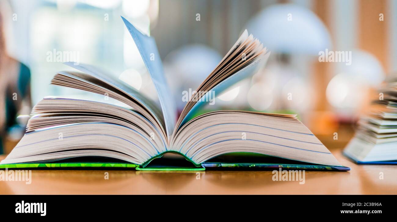 Open book lying on the table in the public library Stock Photo - Alamy