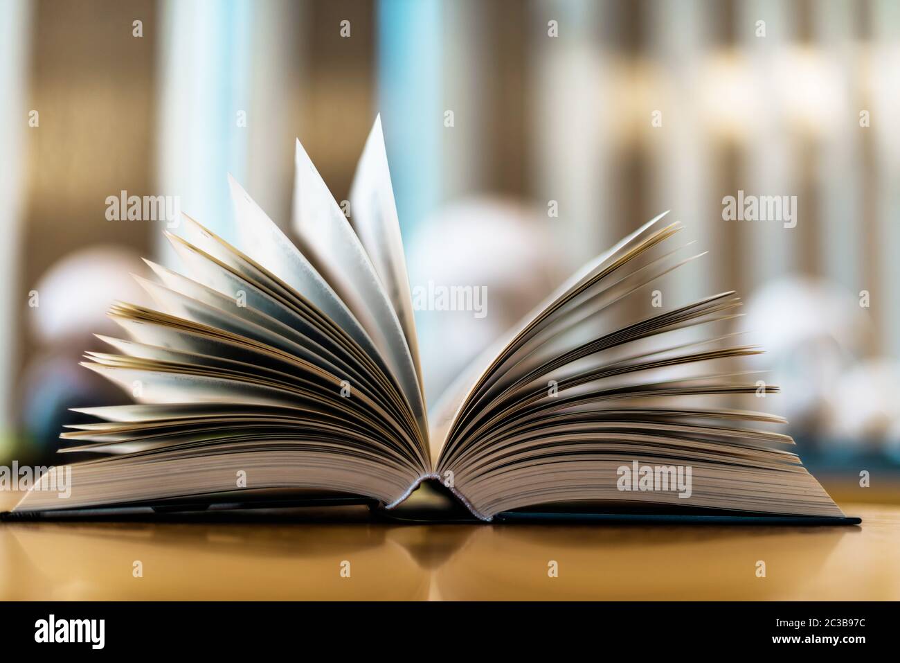 Open book lying on the table in the public library Stock Photo - Alamy