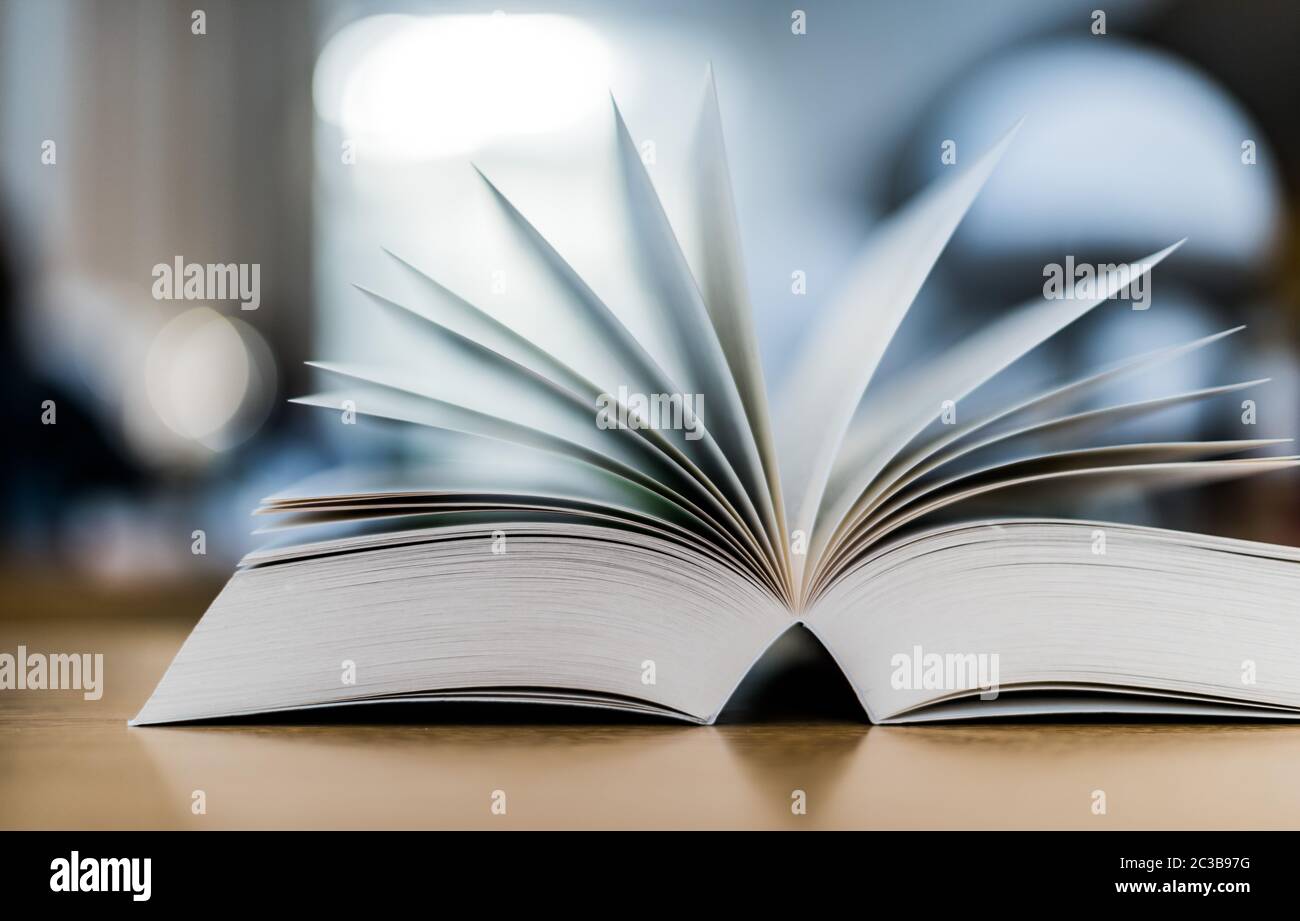 Open book lying on the table in the public library Stock Photo - Alamy