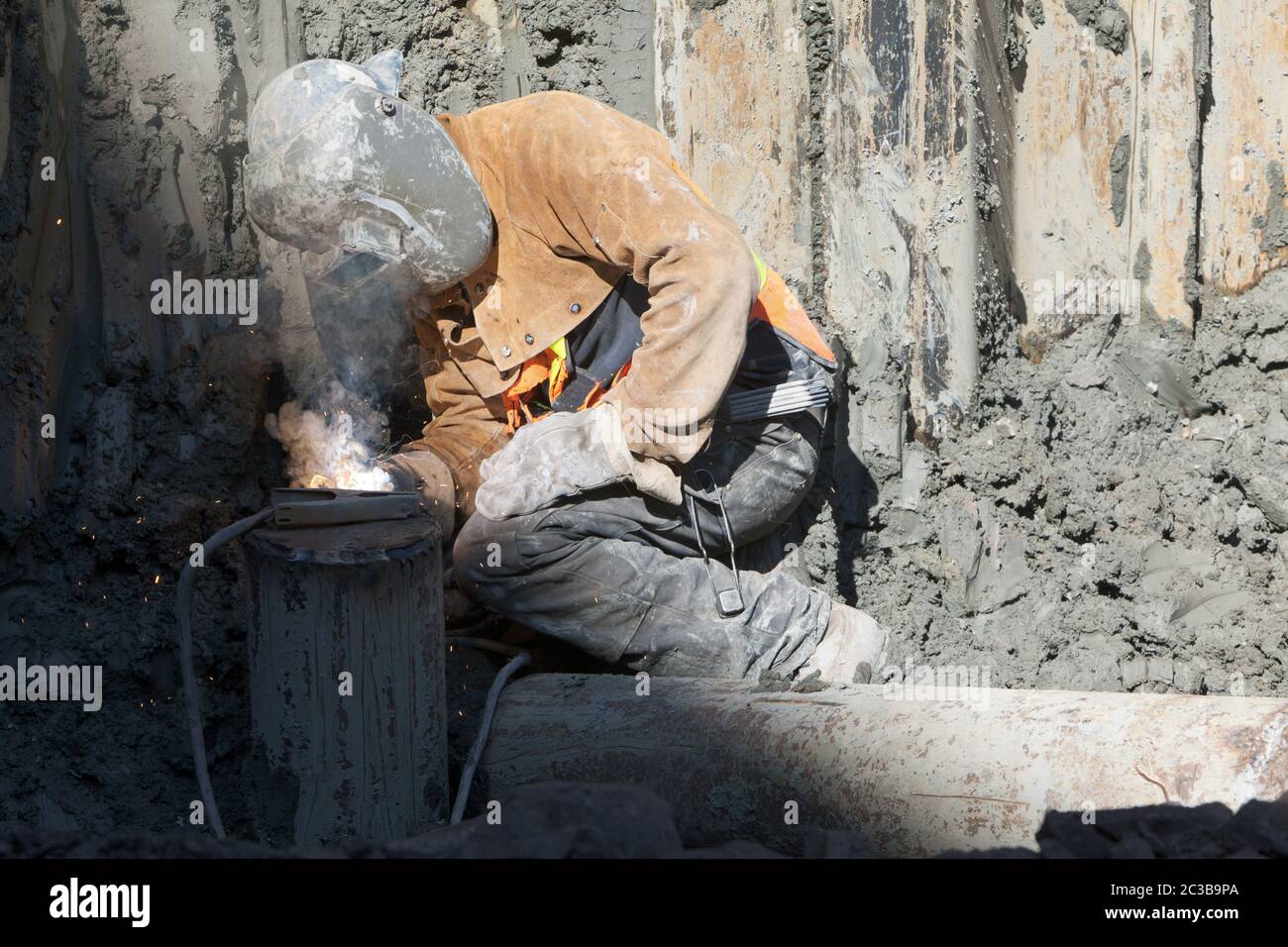 Construction worker welding a steel pipe for the foundation of a new ...