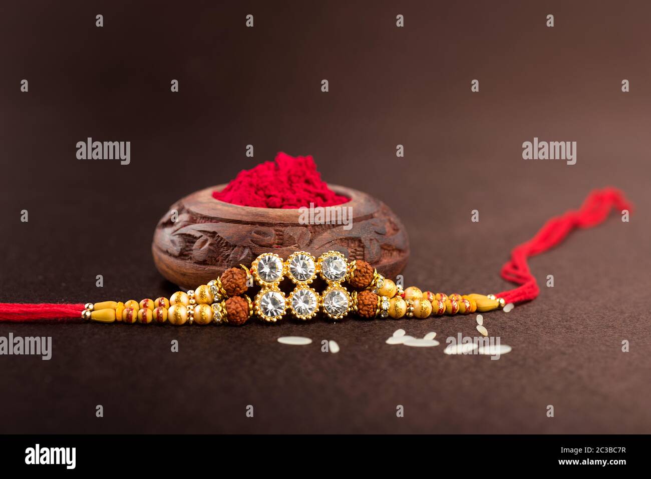 Raksha Bandhan background with an elegant Rakhi, Rice Grains and Kumkum ...