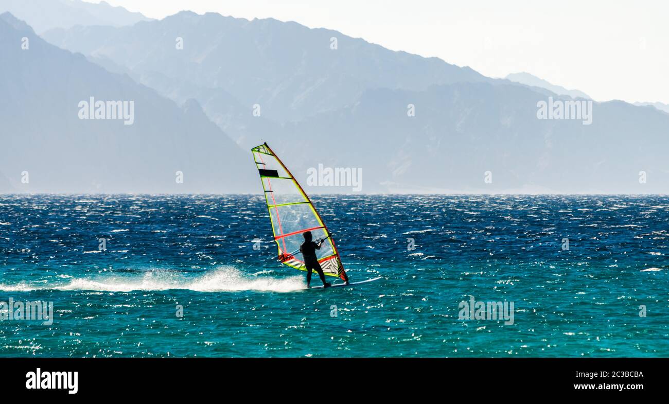 one surfer rides a sail in the Red Sea against the backdrop of the high ...