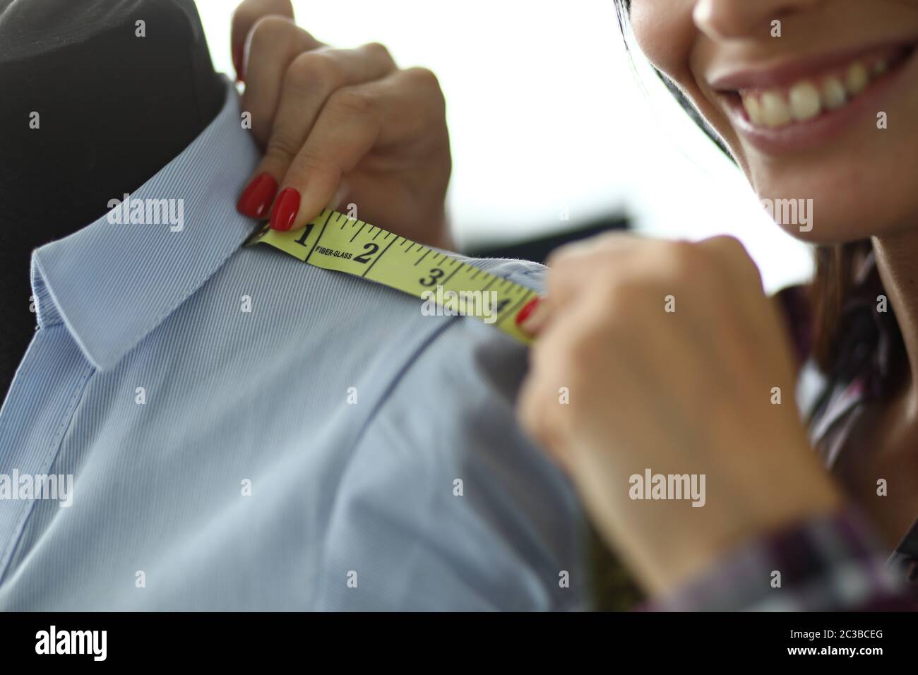Smiling female designer taking measurements on a mannequin Stock Photo ...