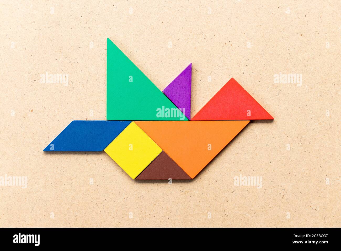 Color tangram puzzle in flying bird shape on wood background Stock ...