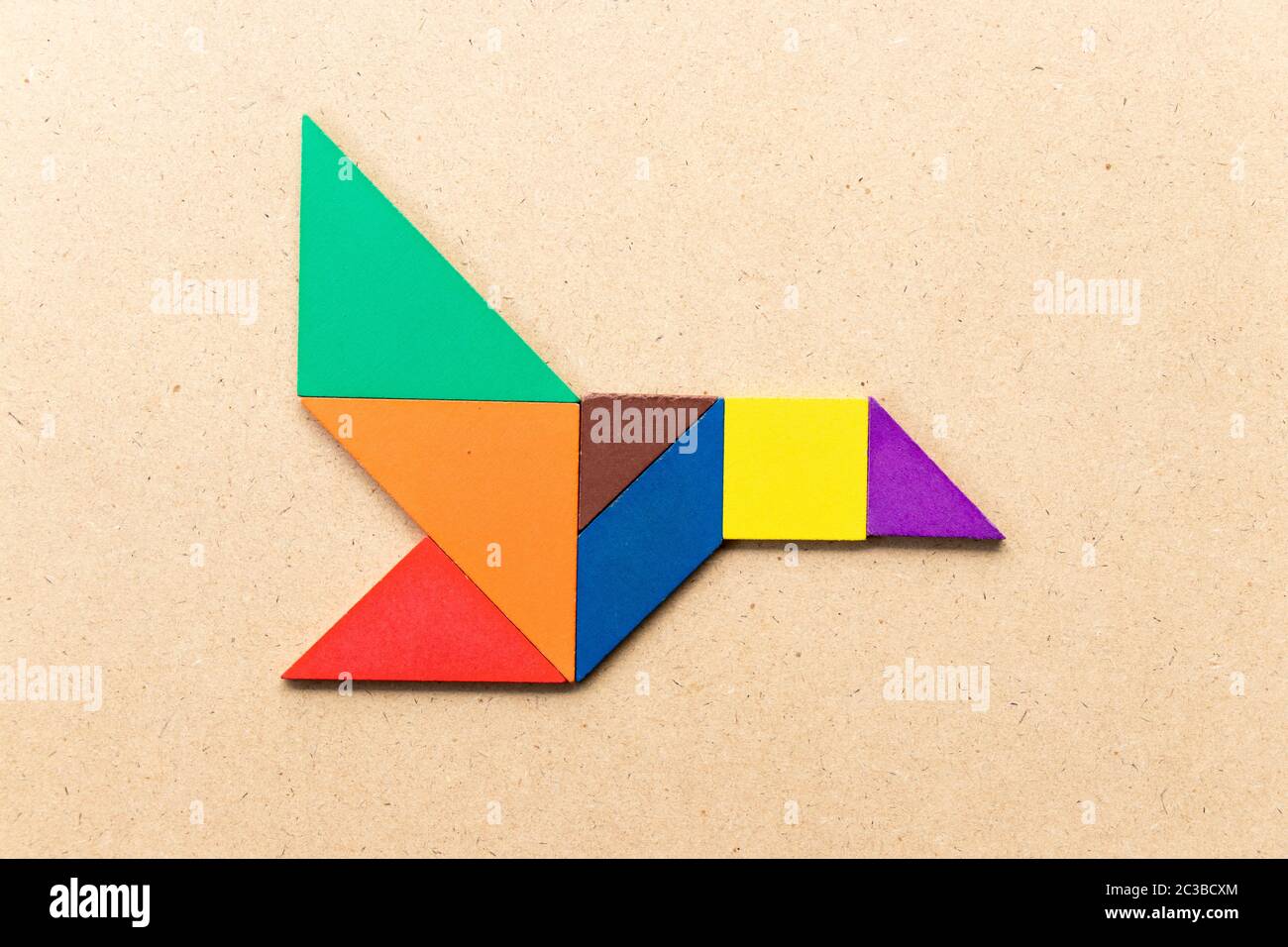 Color tangram puzzle in flying bird shape on wood background Stock ...