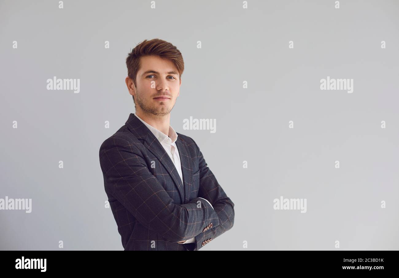 Smiling man crossed his arms in a casual jacket on a gray background ...